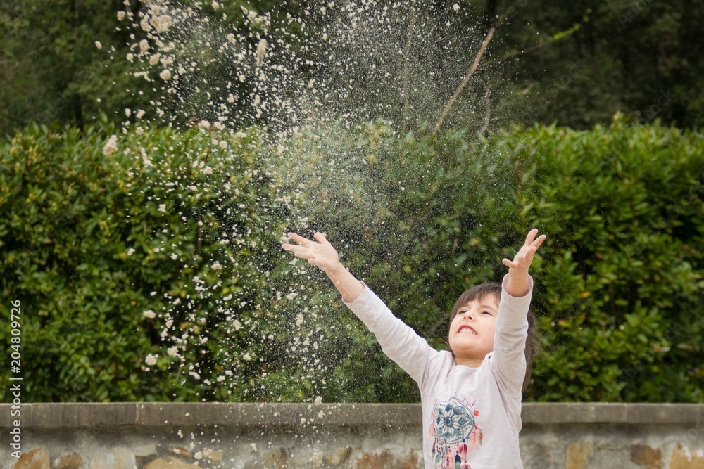 Funny little girl throwing sand in the air with open arms at park in ...