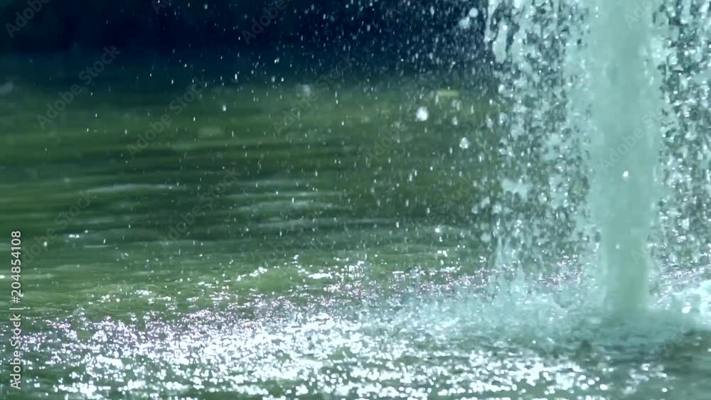Drops and splashes of water from a powerful jet of a fountain fall ...