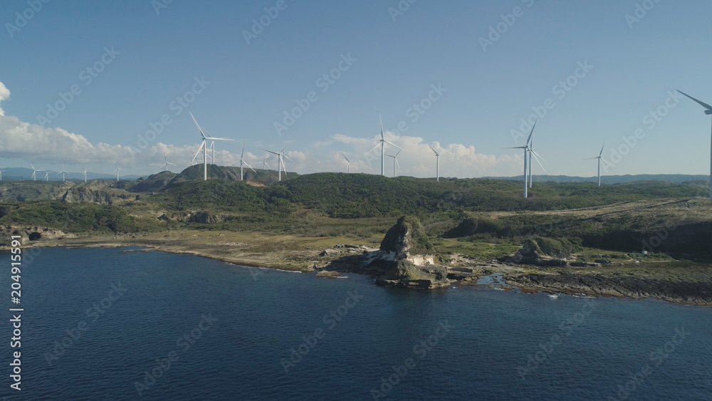 Natural rock formation of limestone stone on the coast with windmills ...