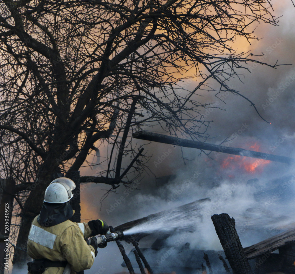 Firefighter extinguishes the fire. Fireman holding a hose with water ...