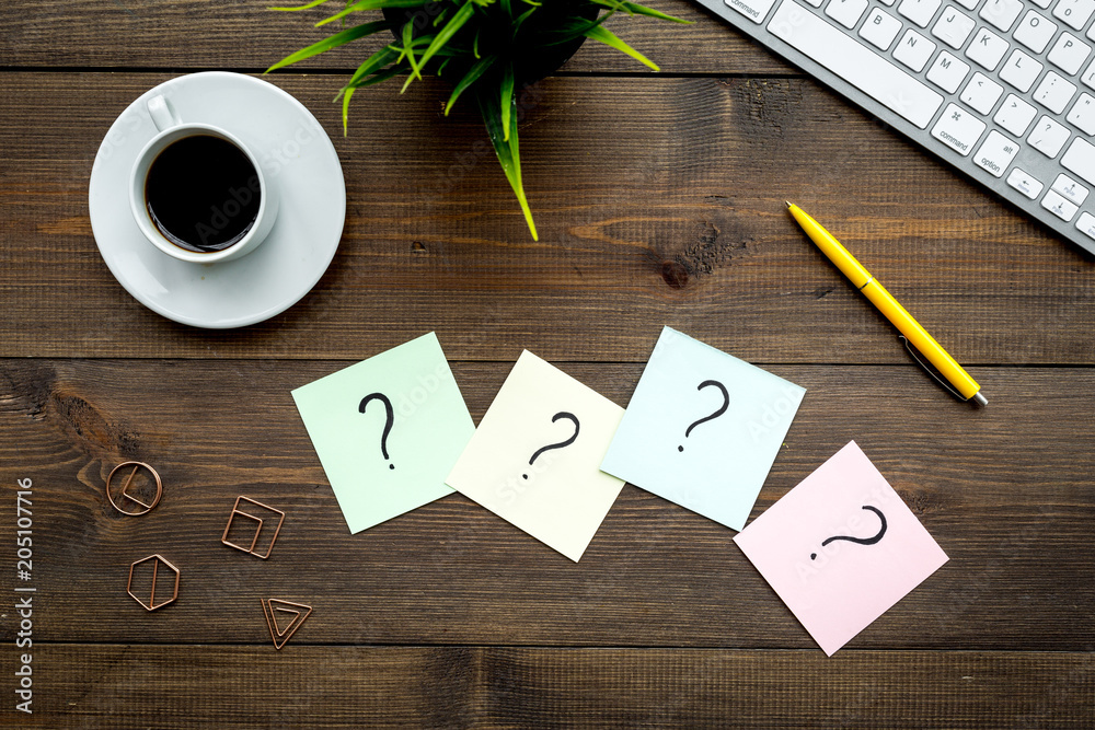 Question mark on sticky notes on office desk on dark wooden background ...