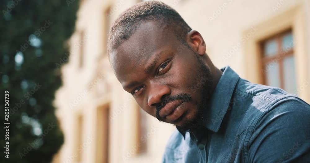 Tired African American man sits on the bench outside. A sad, frustrated ...