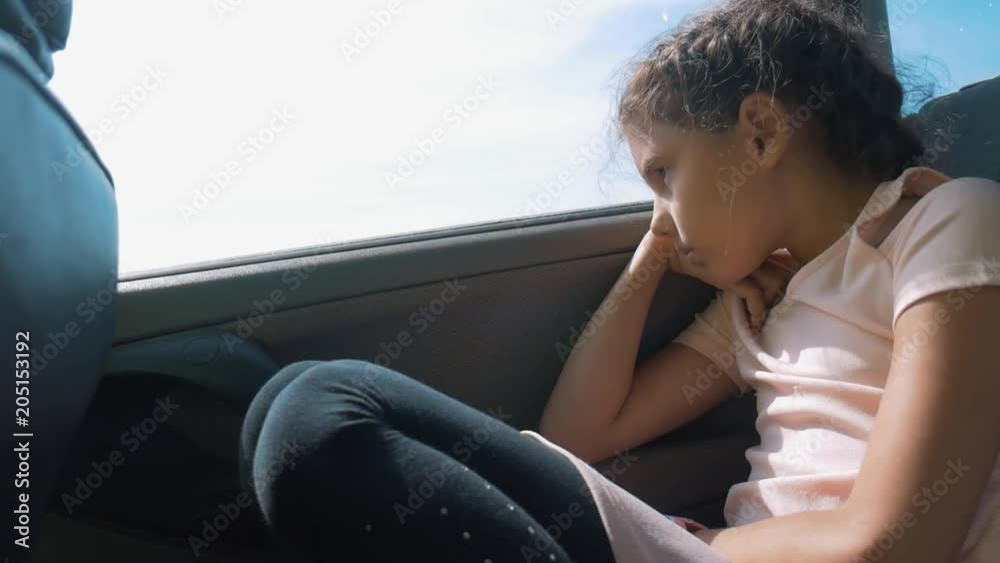 sad girl bored sitting in the car in the back seat motion travel ...
