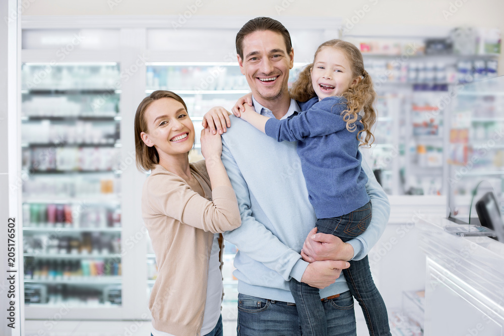 Family together. Exuberant jolly family coming in drugstore and smiling ...
