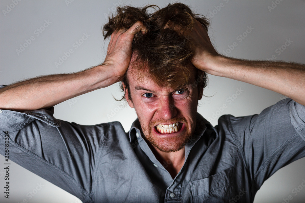 Mad young man with clenched teeth pulling his hair Stock Photo | Adobe ...