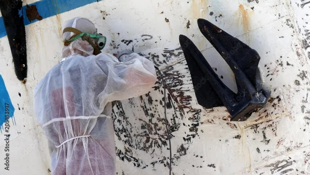Workers tear off paint on metal in repairs process at shipyard. Working ...
