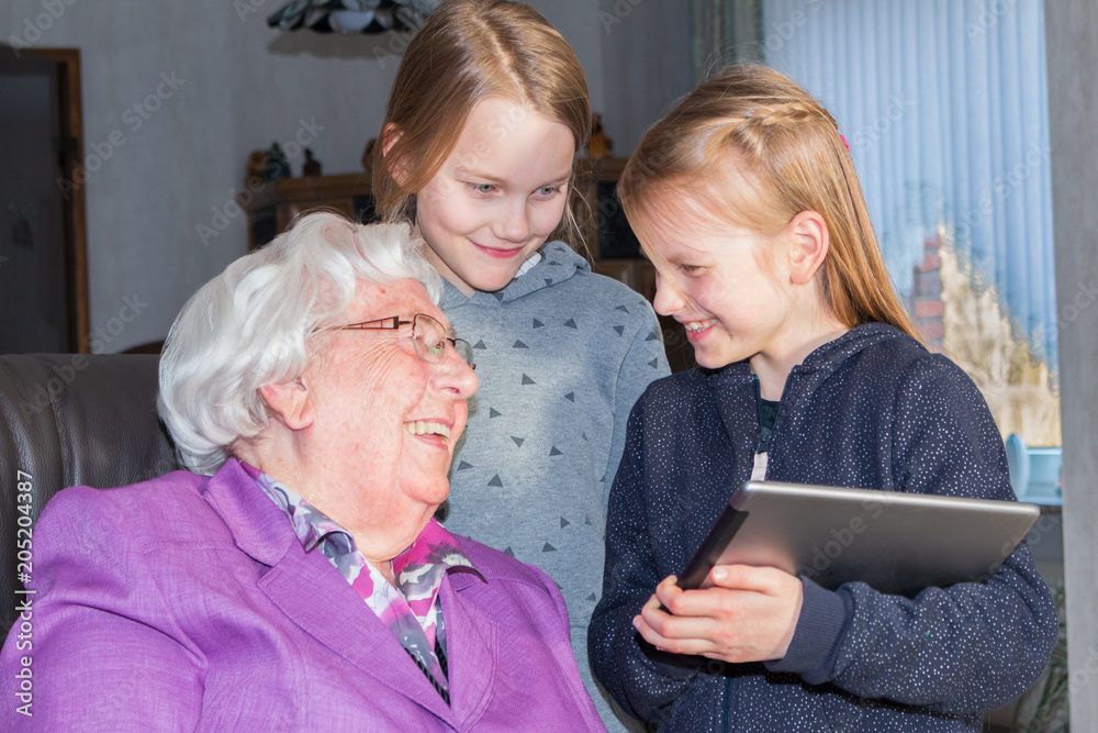Eine Urgroßmutter lacht ihre Enkelinen an Stock Photo | Adobe Stock