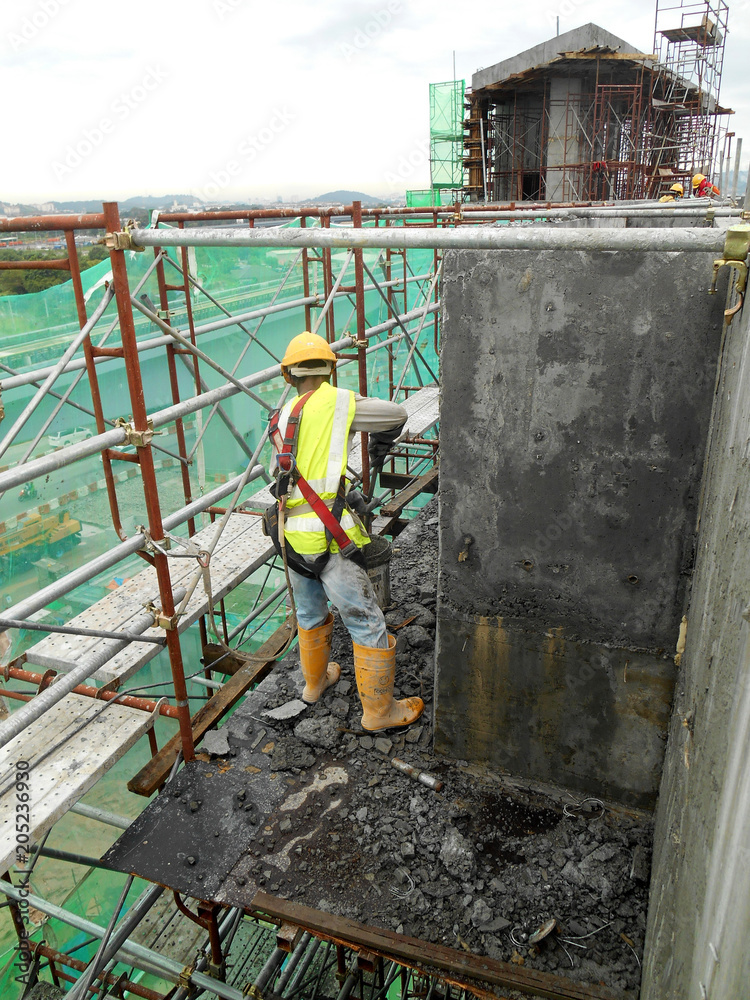 Construction workers working at height at the construction site. Using scaffolding as the ...