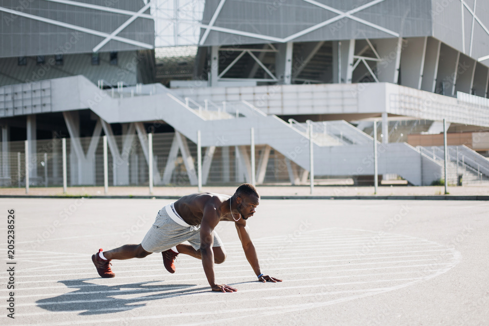 Attractive African American man does burpees working out on the street ...