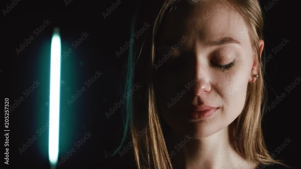A woman is crying in the dark. She is very sad. Tears flow down her ...