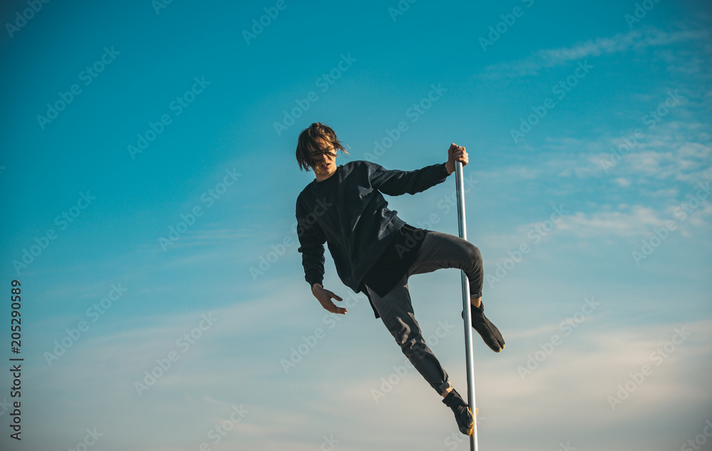 Foto Stock Pole dance sport. Sexy macho man fly on blue sky background ...