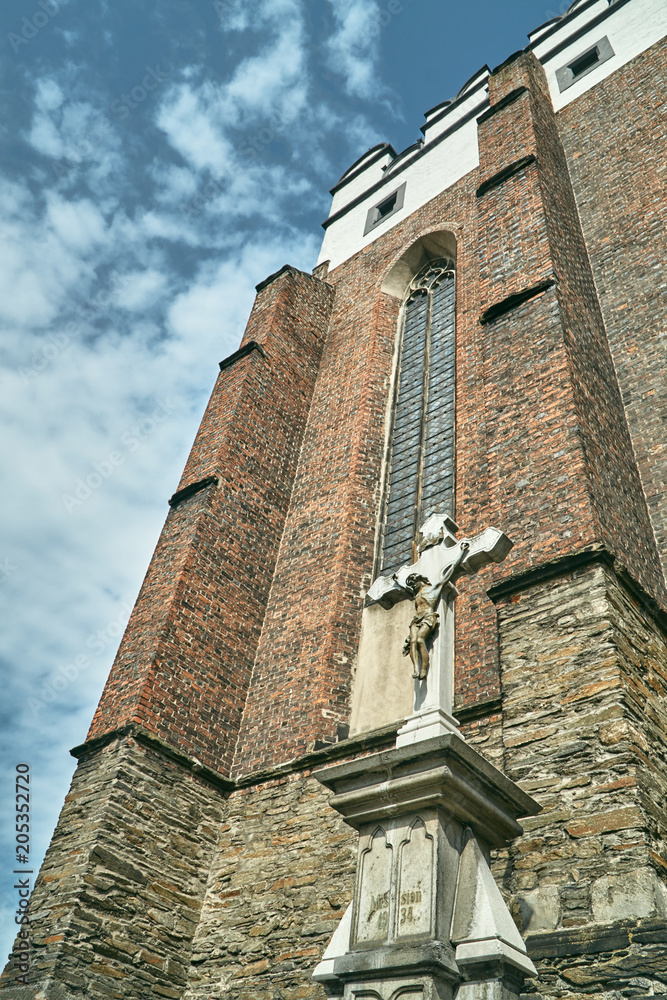Cross and facade of a medieval defensive church in the Gothic style in ...