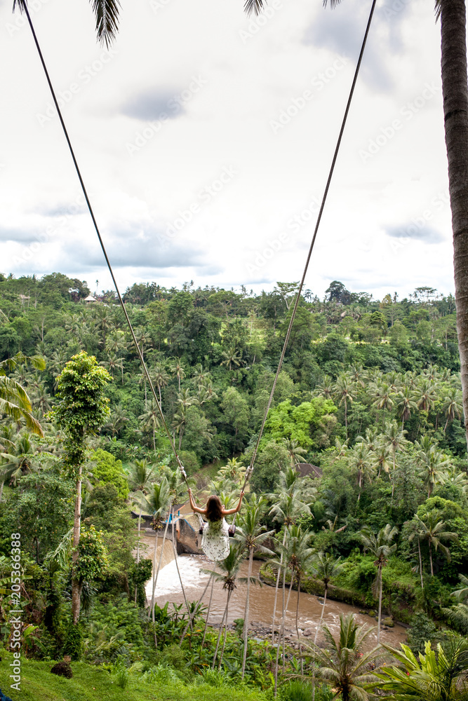 Young tourist woman swinging on the cliff in the jungle rainforest and ...