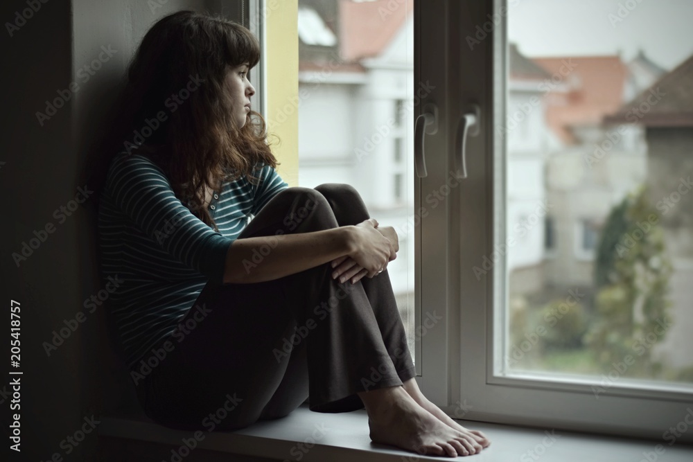 Sad young woman sitting on the window, watching out Stock Photo | Adobe ...