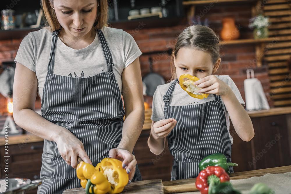 Little girl smelling pepper cut while mother cooking on kitchen. Stock ...