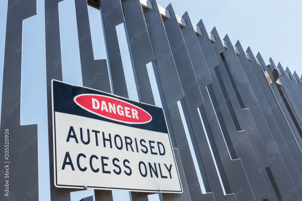 Warning sign against unauthorised access on a high steel fence. Stock ...