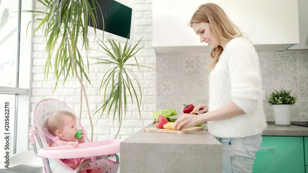 Mother cooking for baby on kitchen. Woman cooking with daughter in baby ...