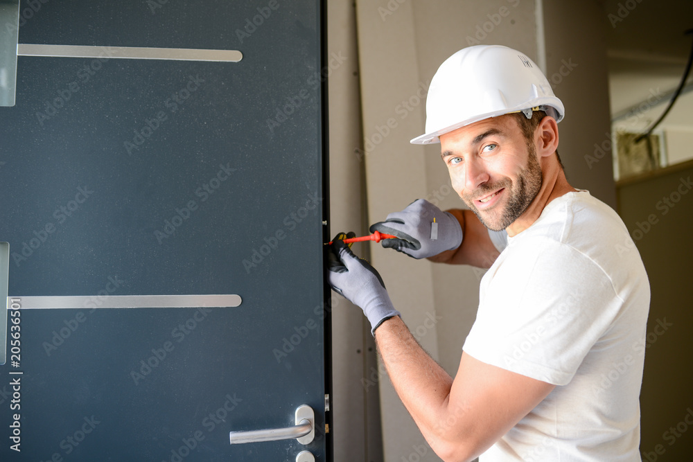 handsome young man installing a door in a new house construction site ...