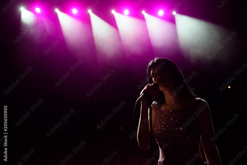 Girl in long gown performing on stage. Girl singing on the stage in ...