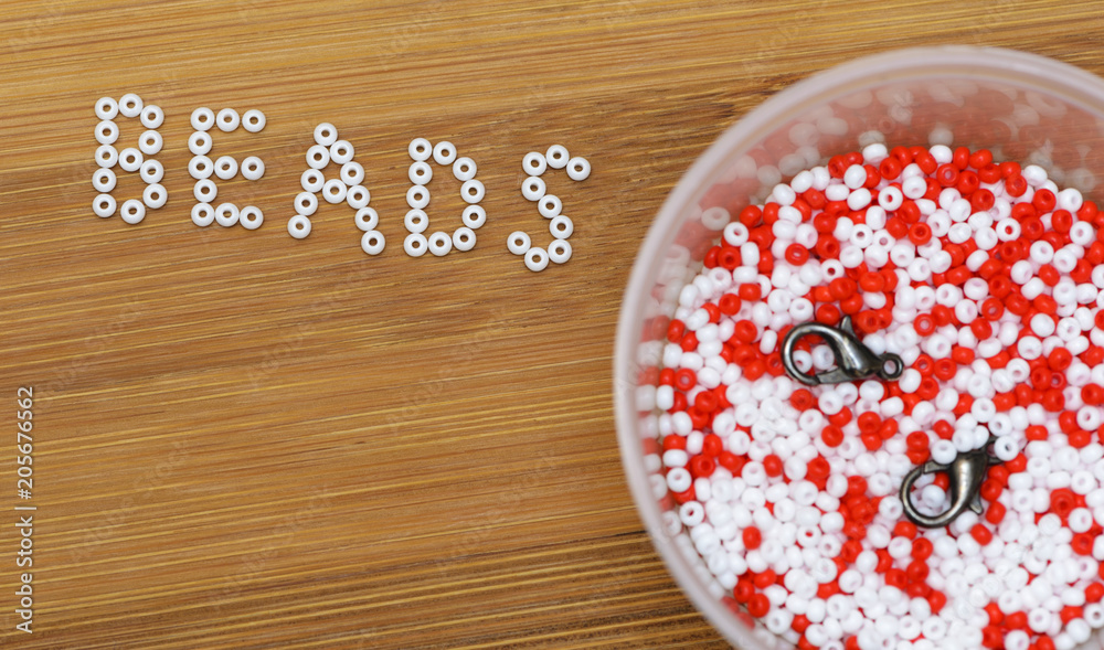 The red and white beads is in a round box on a wood texture. Two ...