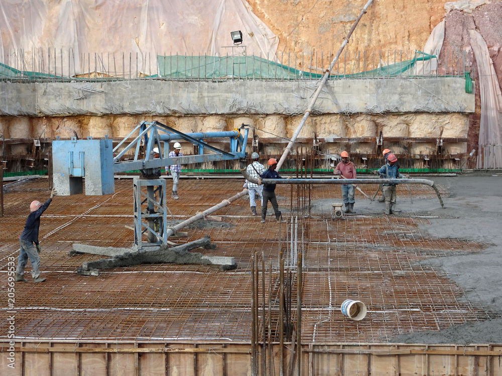 Group of construction workers pouring wet concrete using concrete hose ...