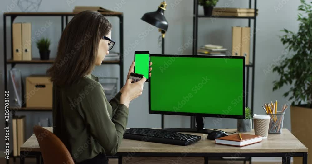 Rear view on the woman in glasses sitting at the office desk in front ...