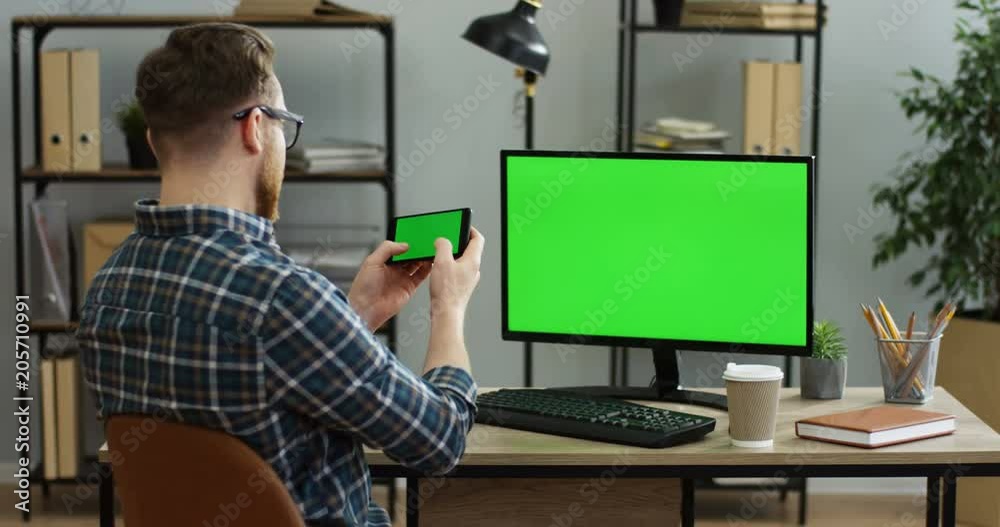 Rear view on the man sitting at the office desk in front of the ...