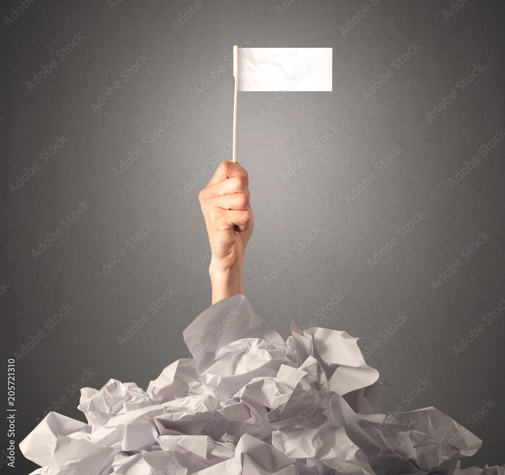 Female hand emerging from crumpled paper pile holding a white blank ...