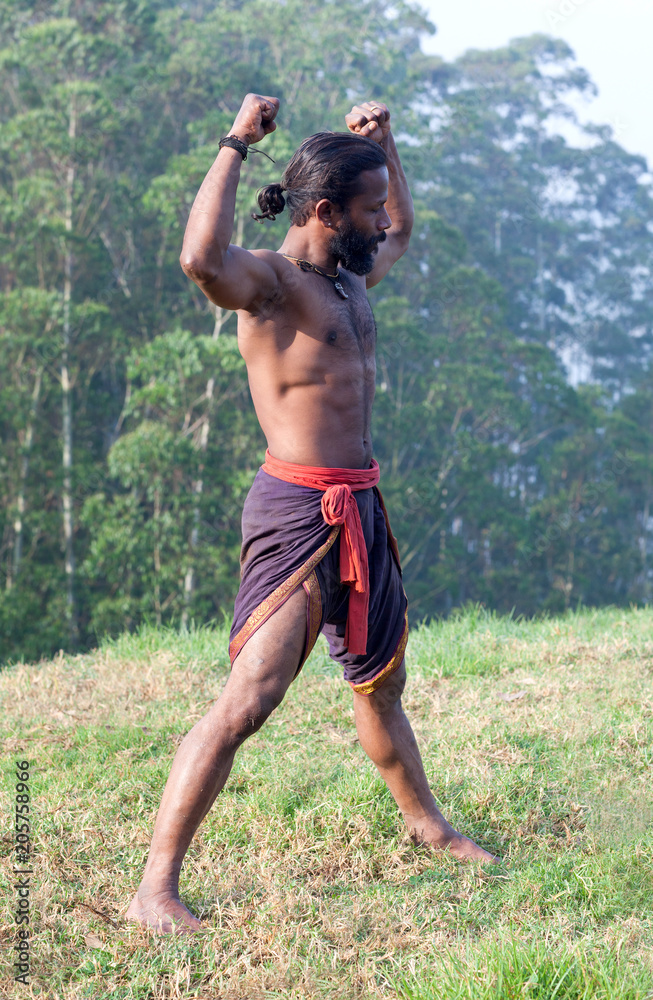 Athletic Indian man doing breathing exercises in standing pose on green ...