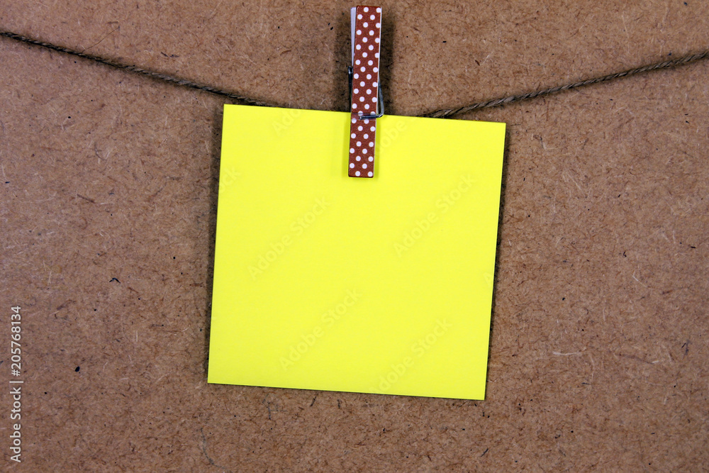 Hoja de papel de color amarillo (posit), sujeto con una pequeña pinza ...