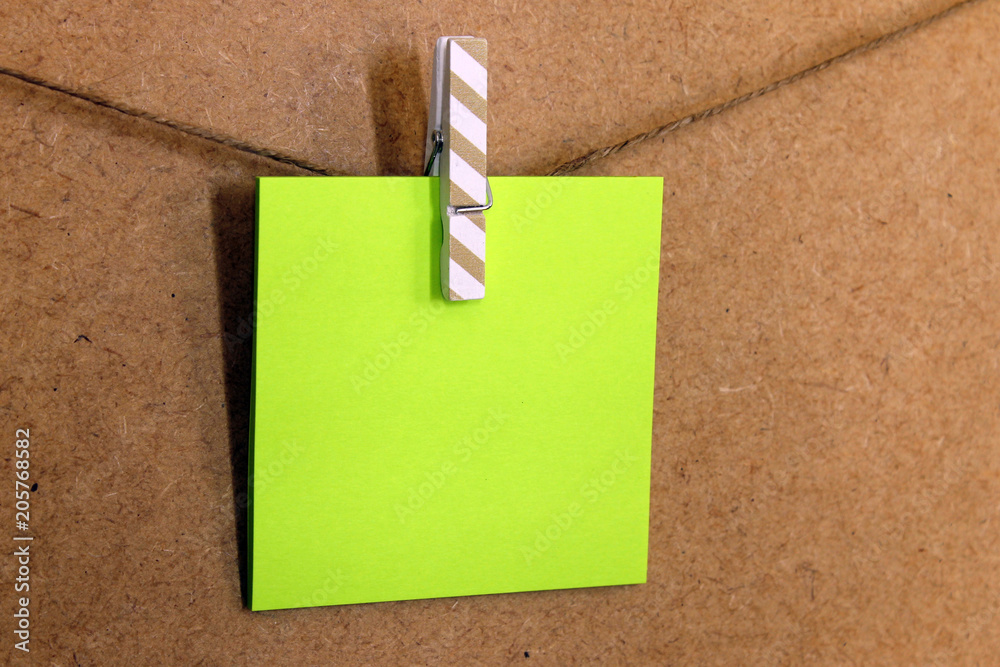 Hoja de papel de color verde (posit), sujeto con una pequeña pinza de ...