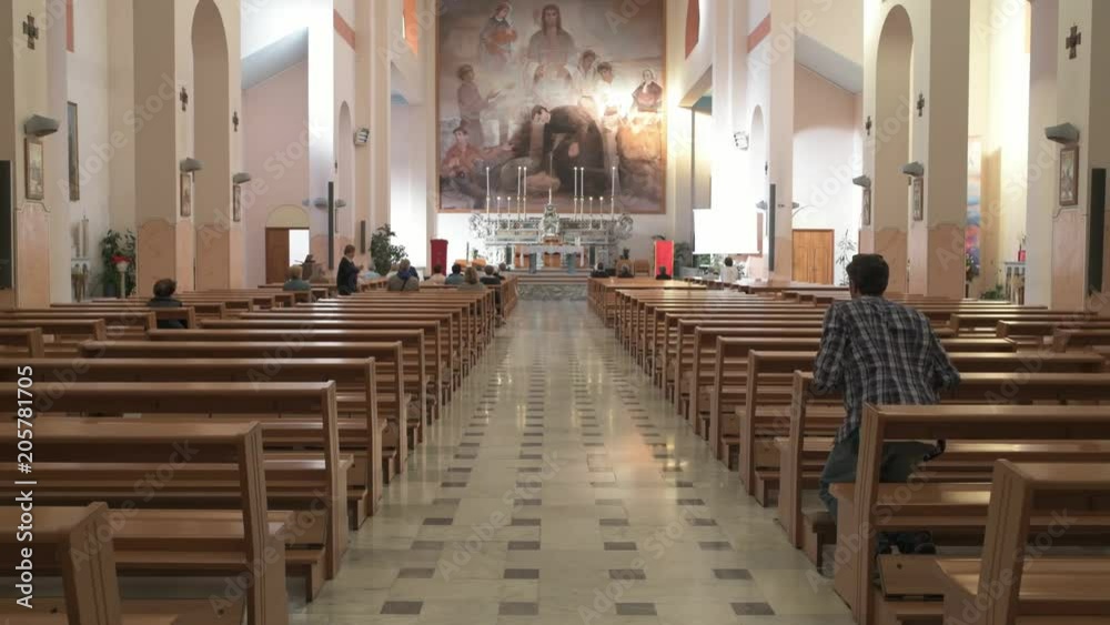 Young man praying in church, kneeling down and making the sign of the ...
