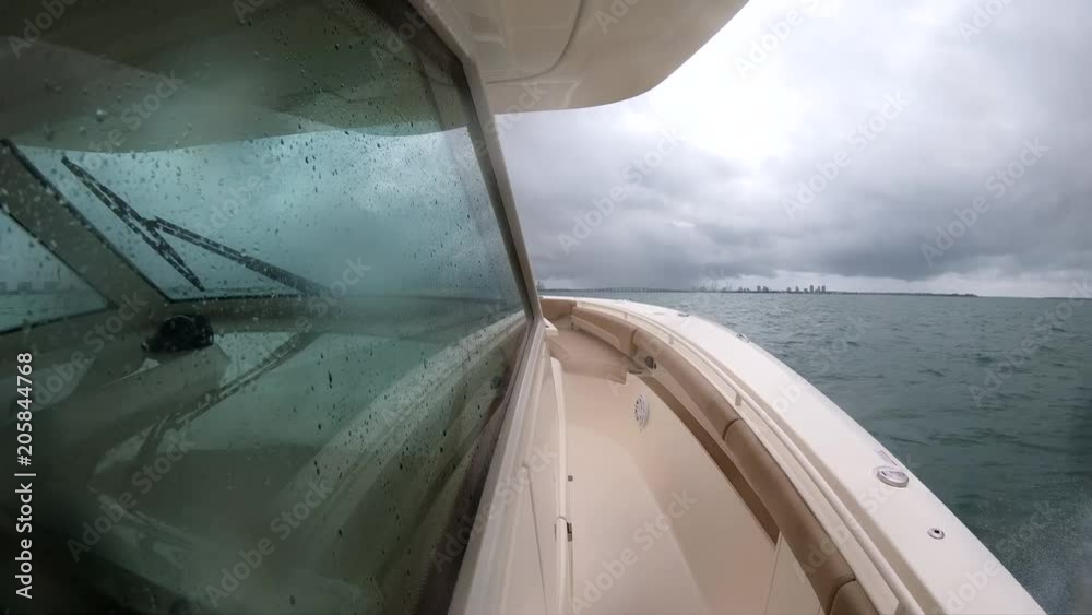 On board lateral view of a boat navigating under heavy rain outside ...