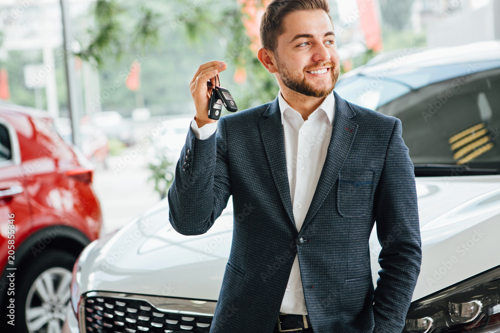 Man is holding a key of their new car, looking at camera and smiling ...