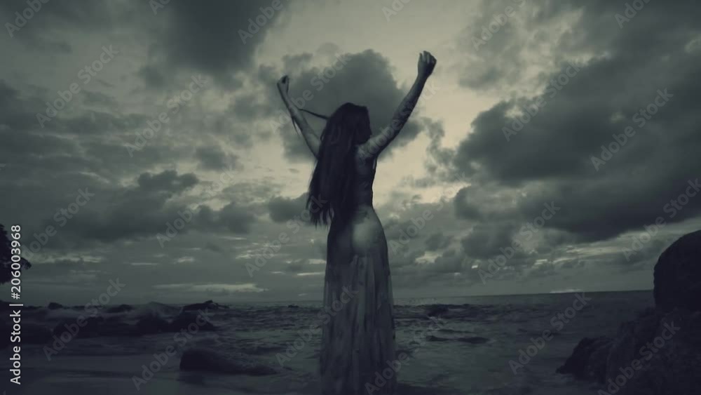 Back view of beautiful mysterious woman in long dress at the sandy ...
