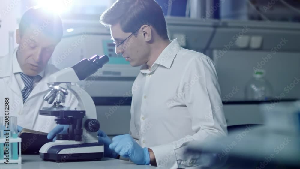 Tracking shot shot of three scientists working in laboratory and ...
