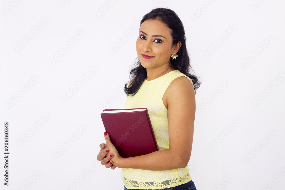 Smiling woman in yellow top holding a book. Side pose Stock Photo ...