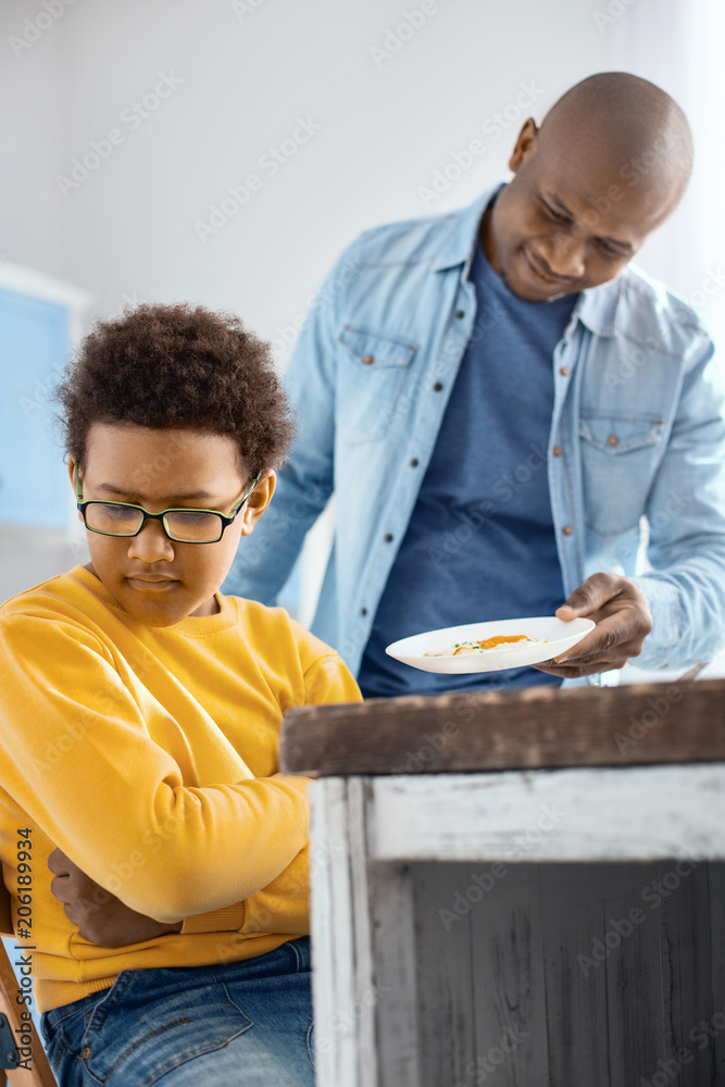 Foto de Have some food. Caring young father giving a plate with a fried ...