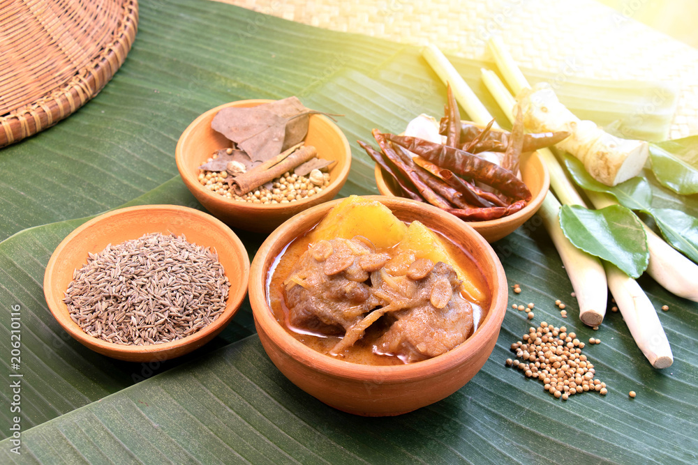 beef mussaman curry in pottery bowl placed on banana leaves with spice ...