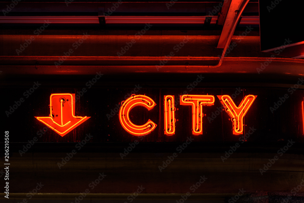 Red neon sign displaying the word "CITY" and a red arrow pointing ...