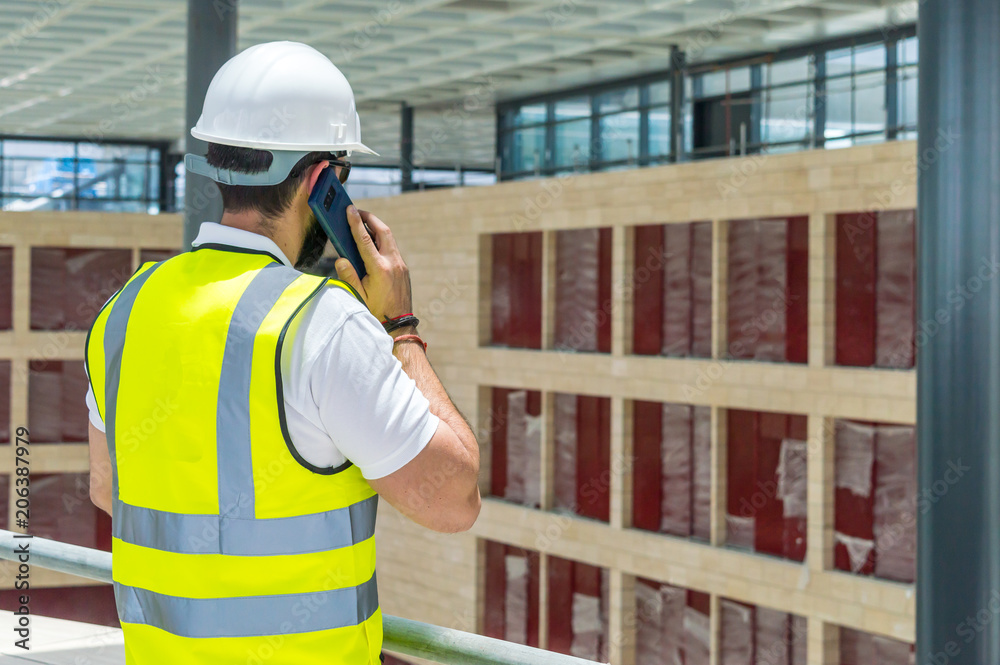 Engineer during a site walk, speaking on the phone giving instructions ...