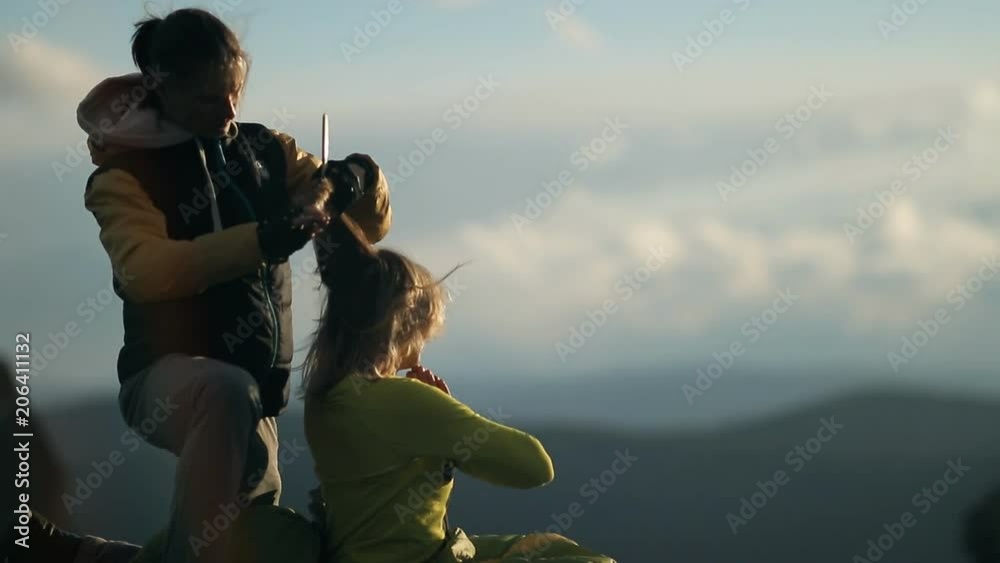 Extreme haircut on top of the cliff. Young male hairdresser doing a ...