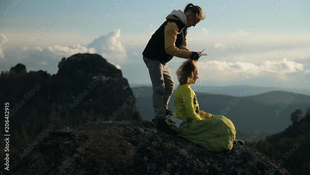 Extreme haircut on top of the cliff. Young male hairdresser doing a ...