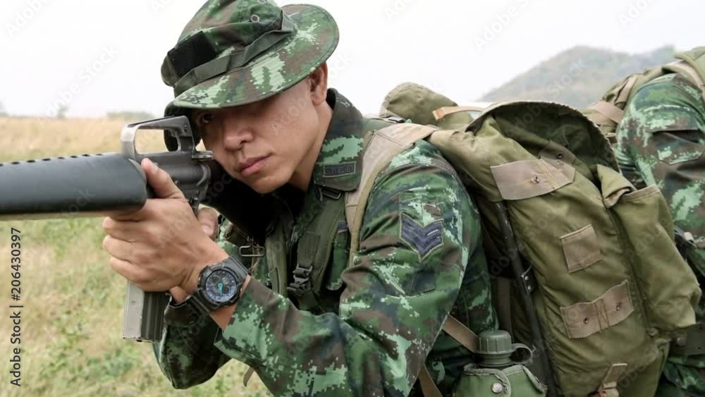 Slow motion of soldier aiming his assault rifle on grass. Chinese ...