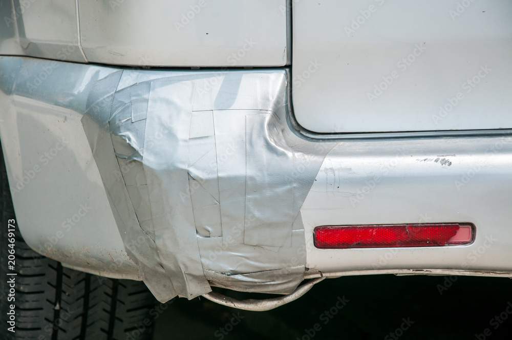 Broken plastic rear end bumper on the silver van glued with duct tape ...