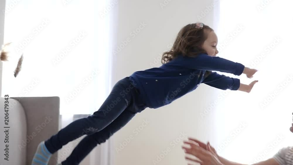 Happy family idyll - little child daughter jump on father arms and they ...