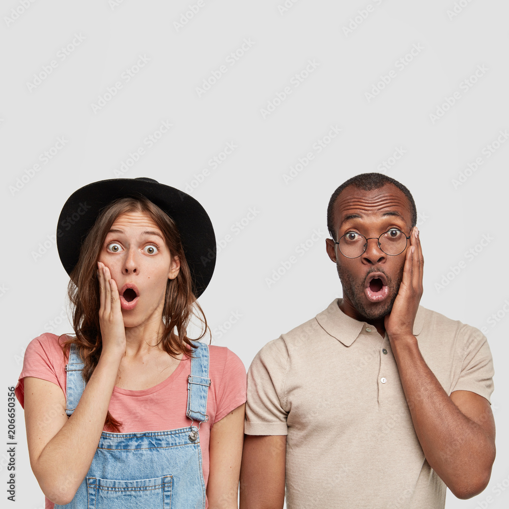 Emotive diverse couple look with stunned frightened expression, being ...
