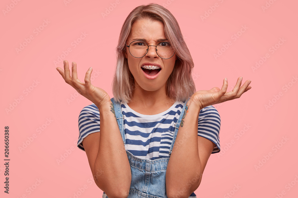 Annoyed indignant young female shrugs shoulders in misunderstanding ...