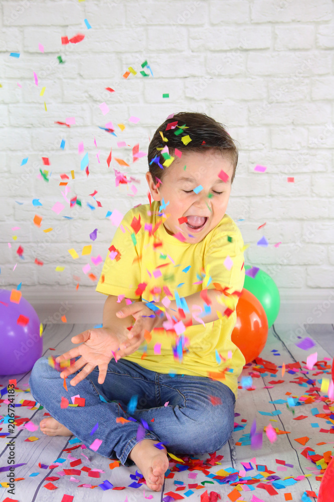 niño pequeño feliz rodeado de globos lanzando confeti de colores Stock ...