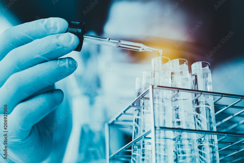 Laboratory pipette with drop of liquid over glass test tubes for an ...